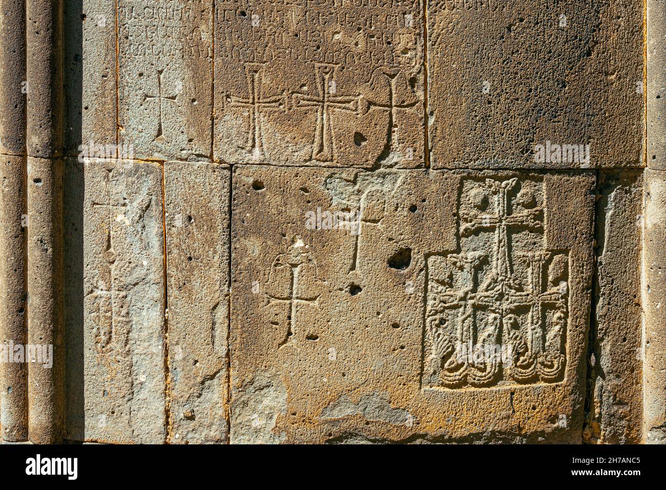 Wall of an ancient medieval church with carved crosses and religious ...