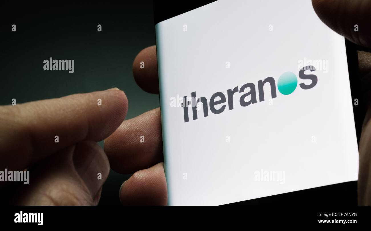Theranos company logo seen on smartphone screen hold in hand. Stafford ...