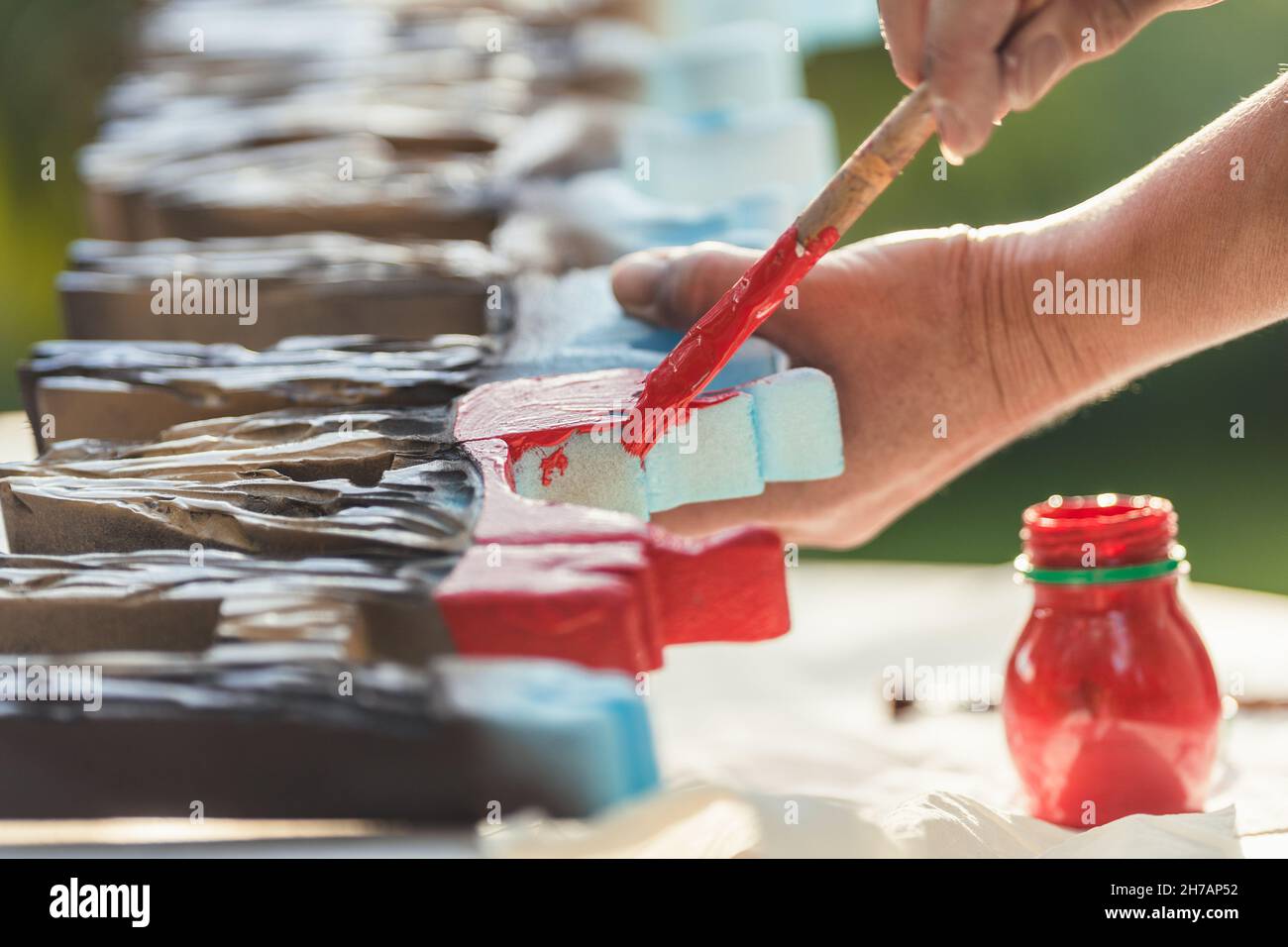 Person painting polystyrene letters in red outside Stock Photo - Alamy