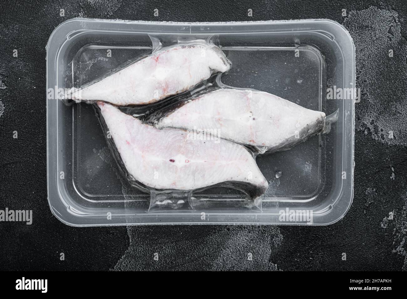 Halibut iced fillet plastic pack set, on black dark stone table ...