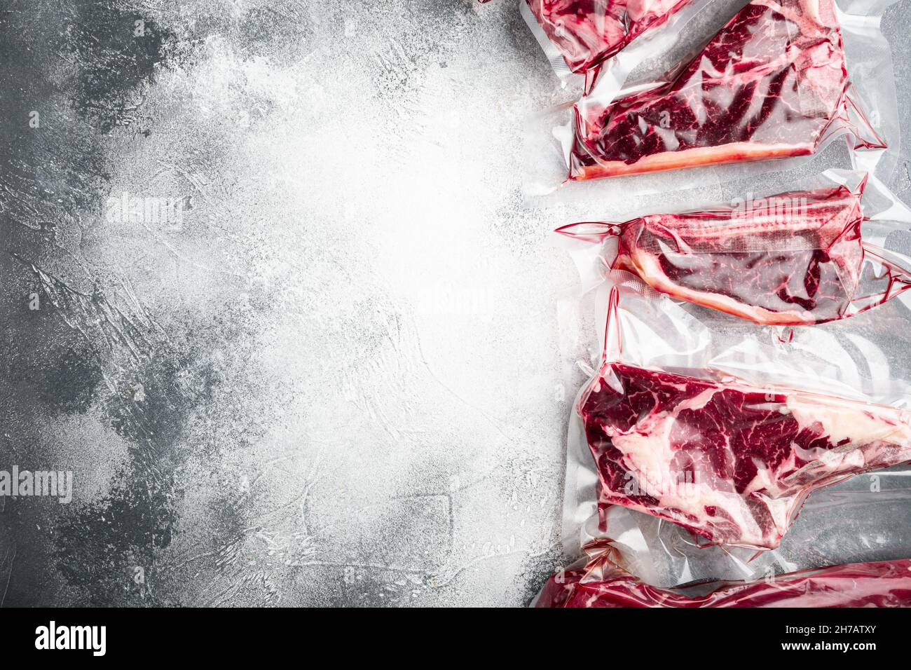 Fresh tasty raw beef steaks with bone wrapped in vacuum plastic packing ...