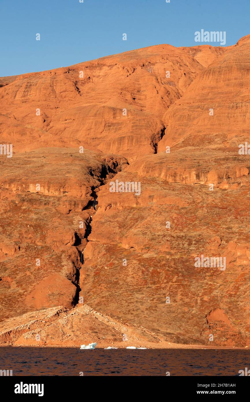 Eroding high iron-rich sedimentary rock cliff eroding with bergy bits ...