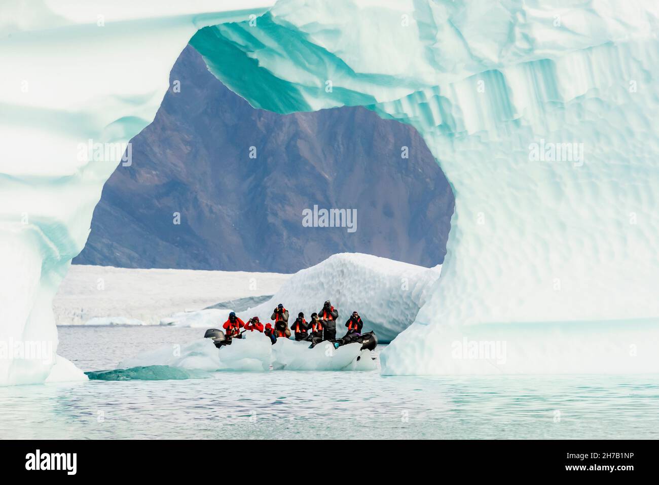 Photographers in zodiac shooting through an ice arch, Rypefjord ...