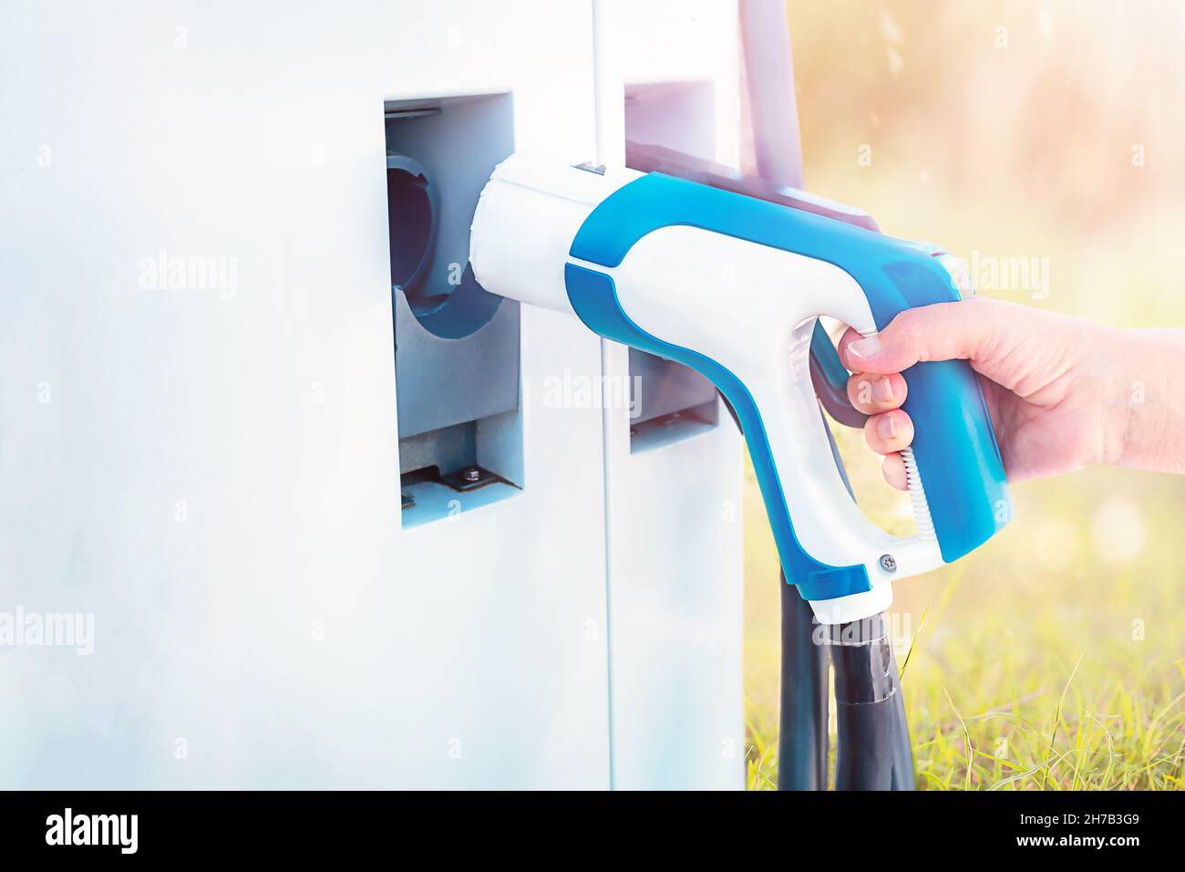 Female hand taking charge for electric cars outdoors. Eco friendly ...