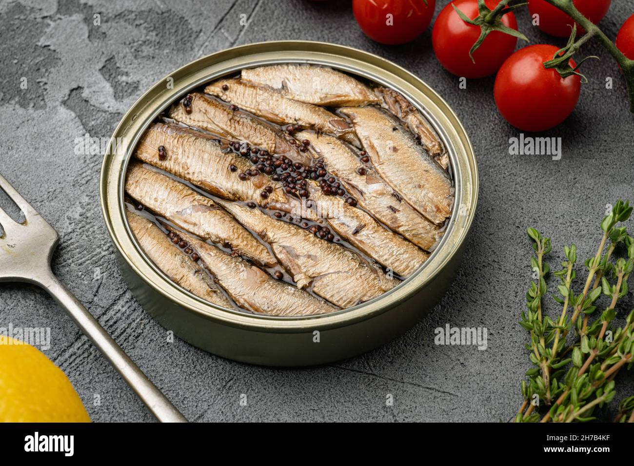 Smoked canned sprats in cooking oil in open tin can set, on gray stone ...
