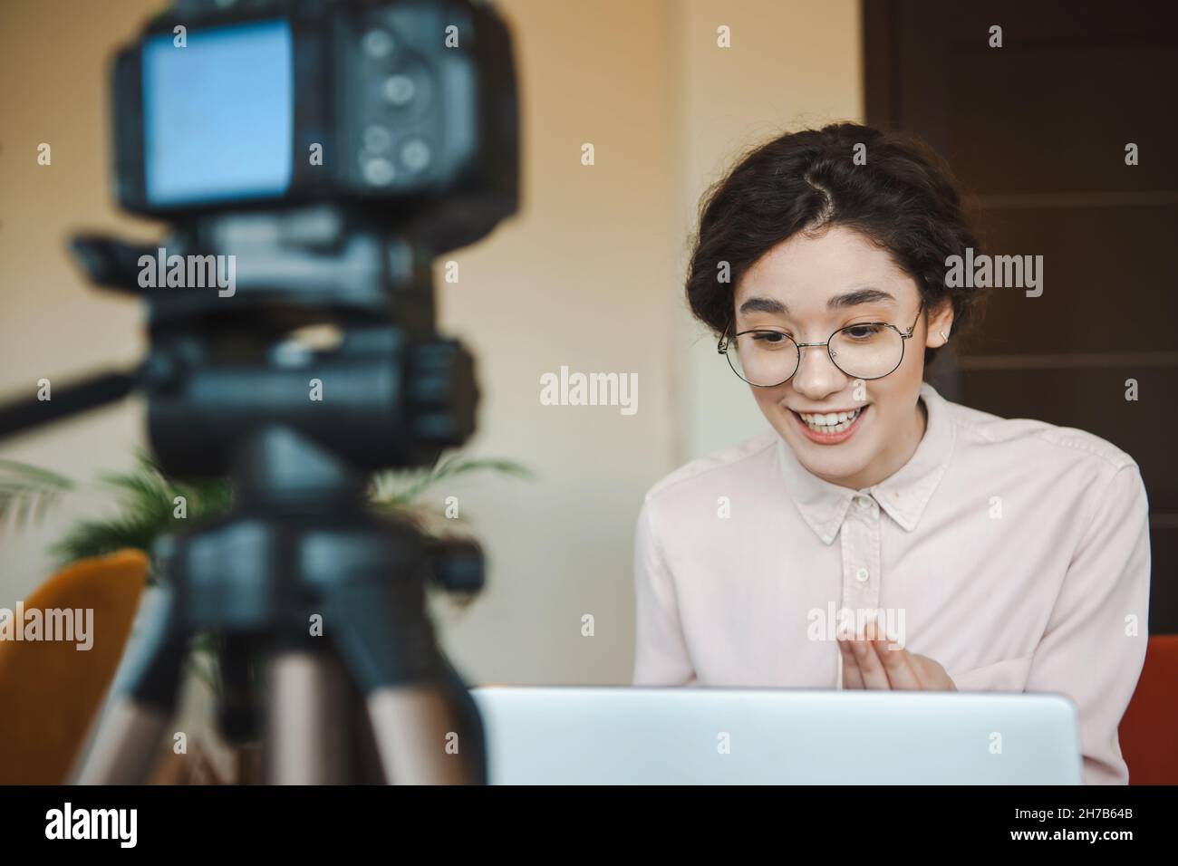 Caucasian woman wearing eyeglasses recording a video lesson on a camera ...