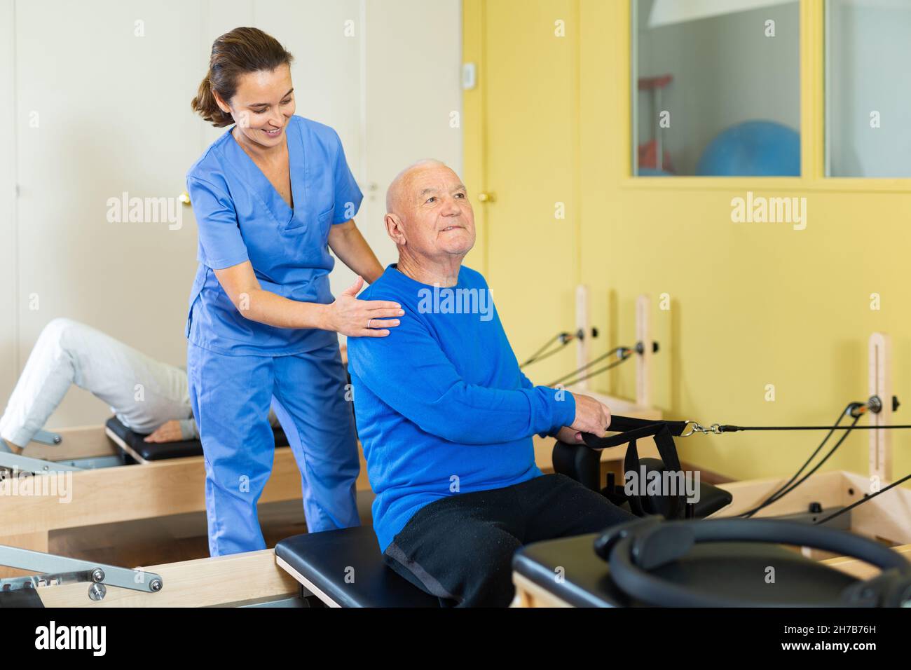 Medical professional helps and monitors the difficulty of Pilates ...