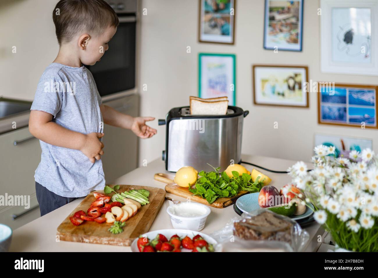 Cute male baby cooking fresh hot sandwiches with cheese, fruits and ...