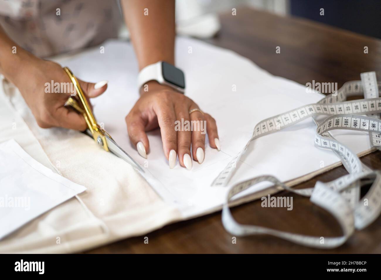 Closeup hands of female professional seamstress cutting textile use ...