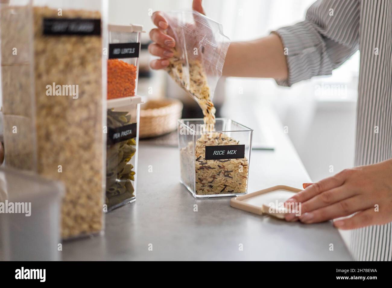 Closeup hands housewife adding rice mix from package into transparent ...