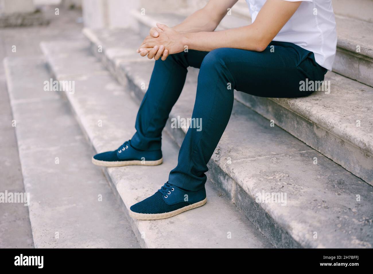 Groom in trousers and sneakers sits on the stone steps Stock Photo - Alamy