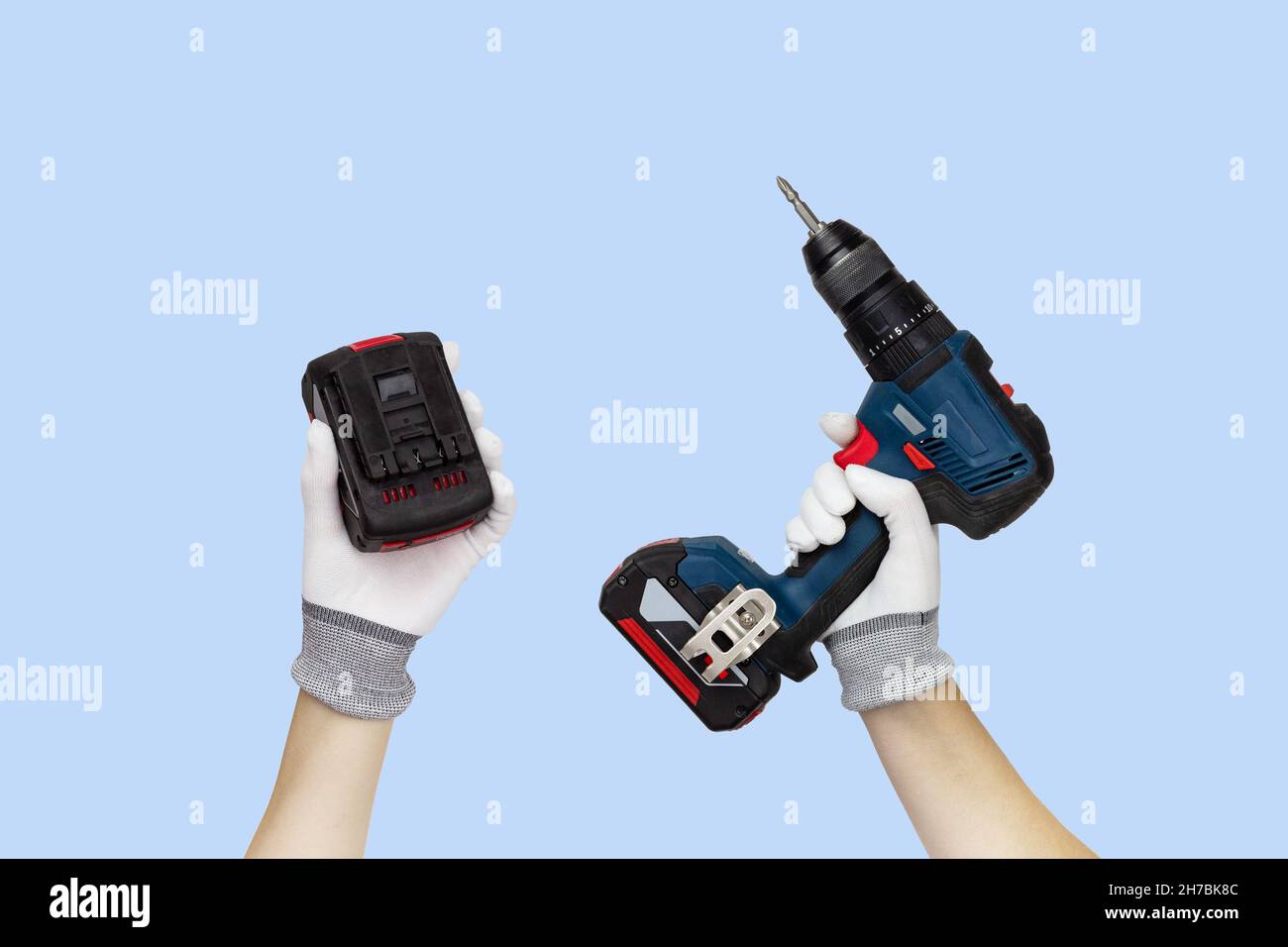 Gloved hands holding screwdriver, drill and battery construction tools ...