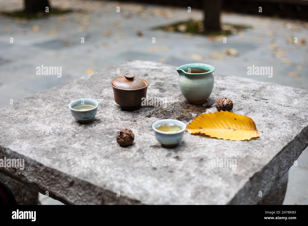 Traditional Chinese tea in a park. Cups and vessels on a stone table ...