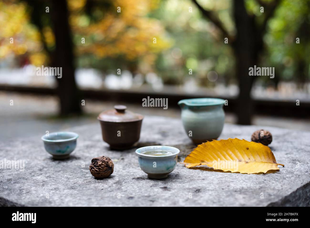 Traditional Chinese tea in a park. Cups and vessels on a stone table ...
