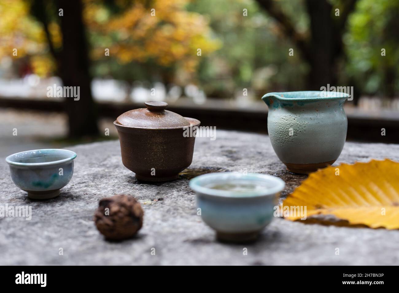 Traditional Chinese tea in a park. Cups and vessels on a stone table ...