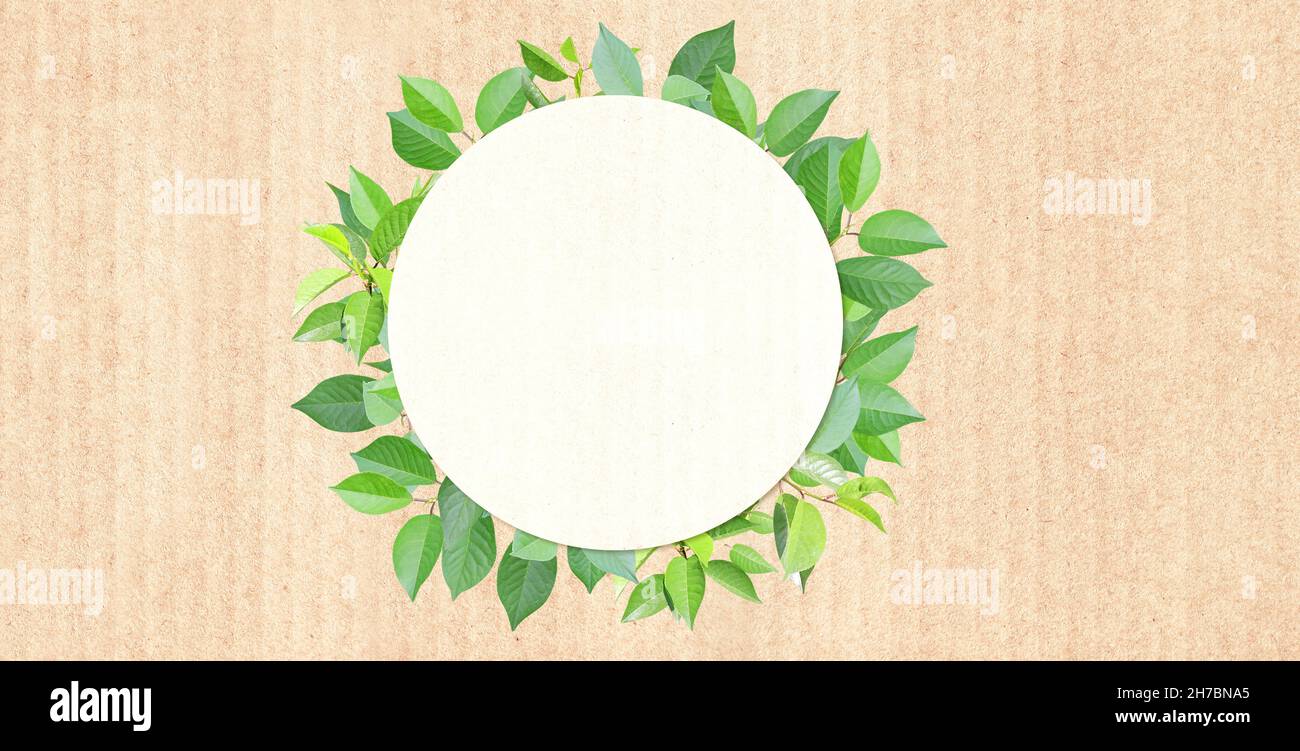 Green leaves and round paper label on cardboard texture. Horizontal ...