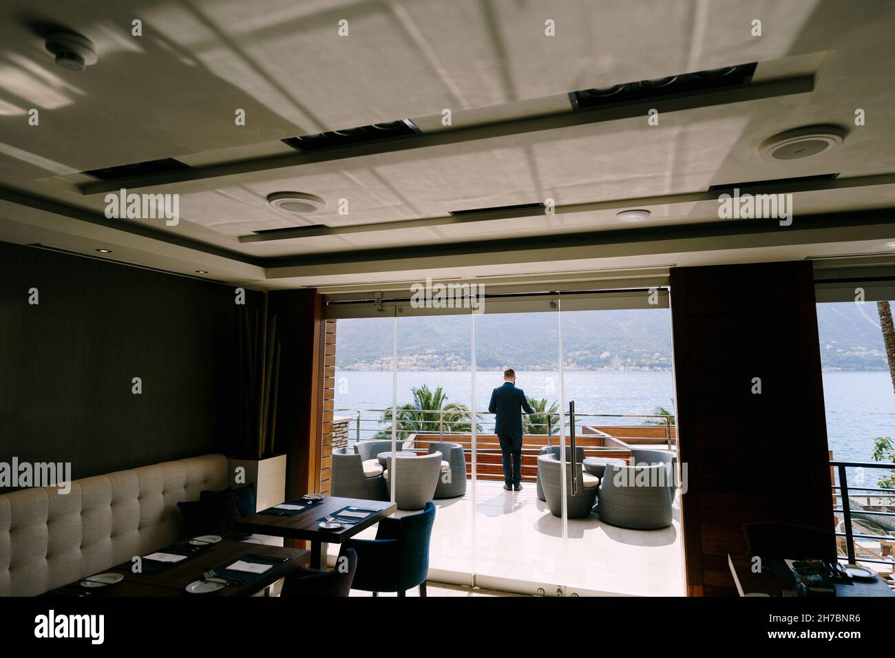 Man stands on the balcony of a luxury hotel and looks out to the sea ...