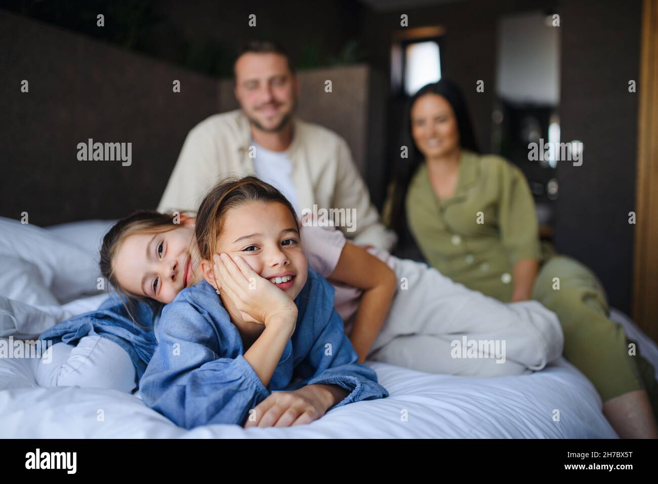 Happy young family with two children lying on bed at hotel, summer ...