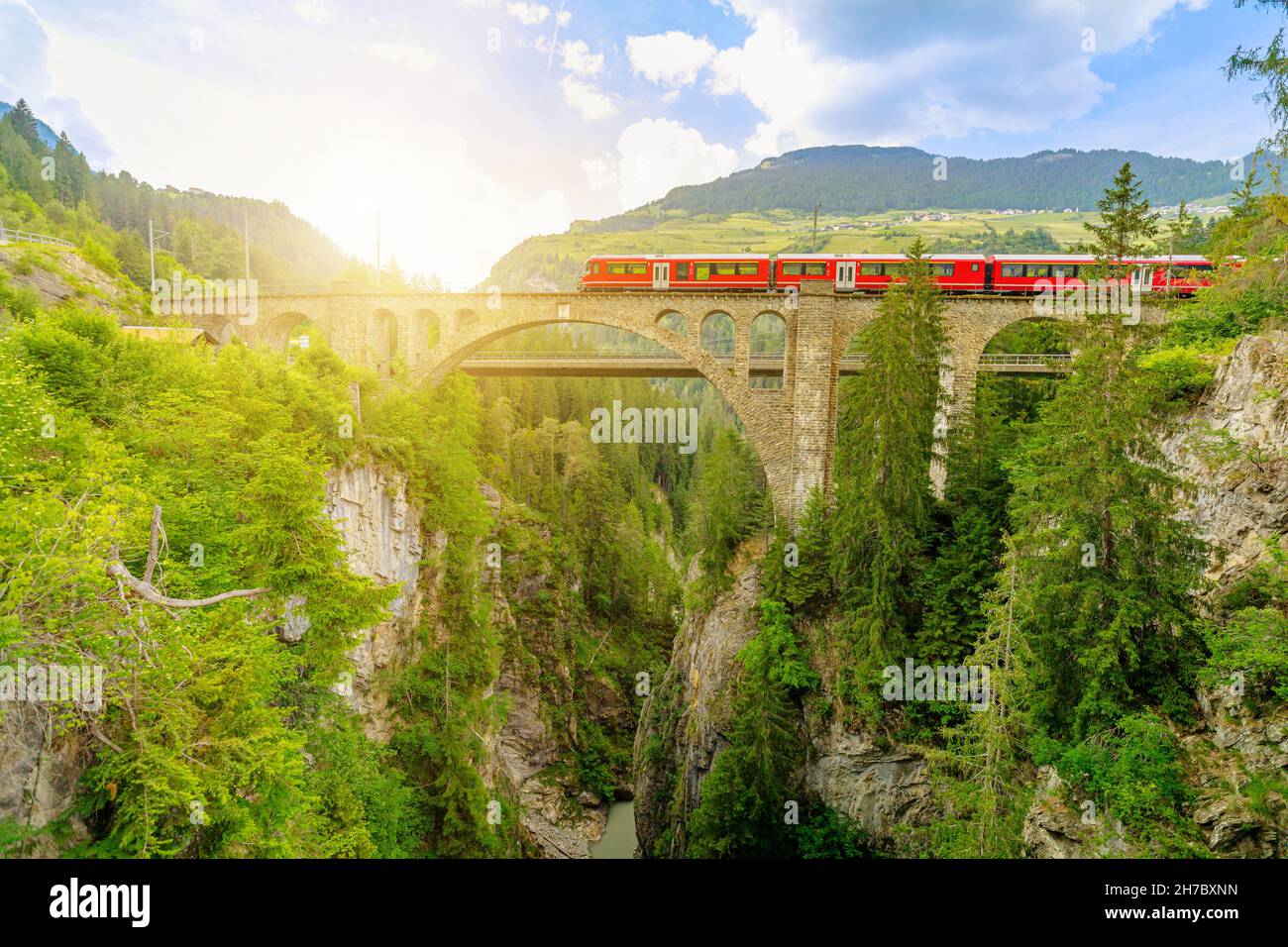 Red train crossing the Solis Viaduct bridge of Swiss railway in ...