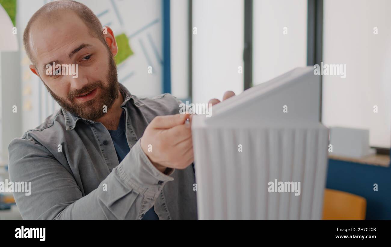 Close Up Of Man Analyzing Building Model With Woman Using Blueprints Plan On Table Colleagues