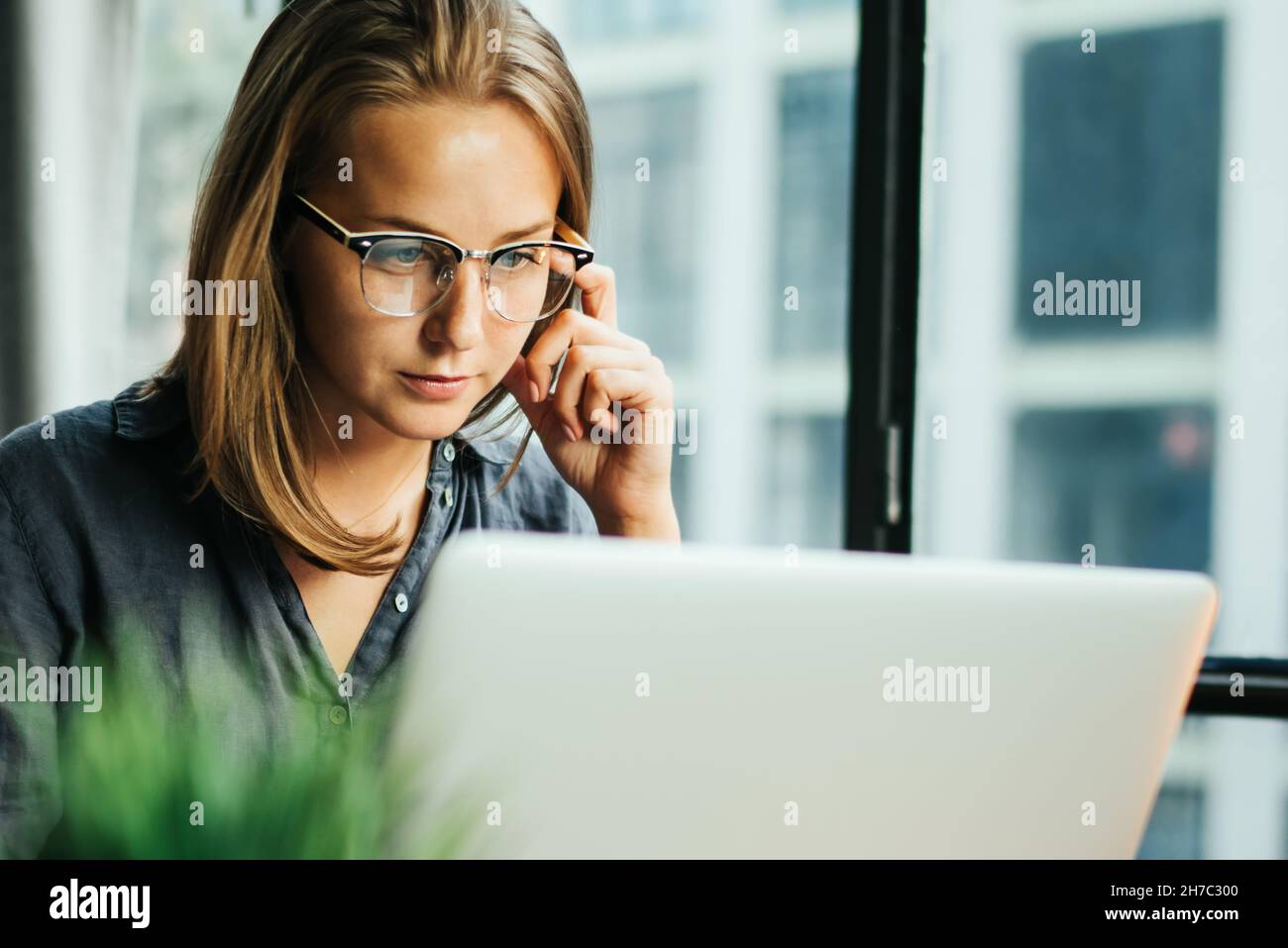 Young woman working with a laptop. Female freelancer connecting to ...