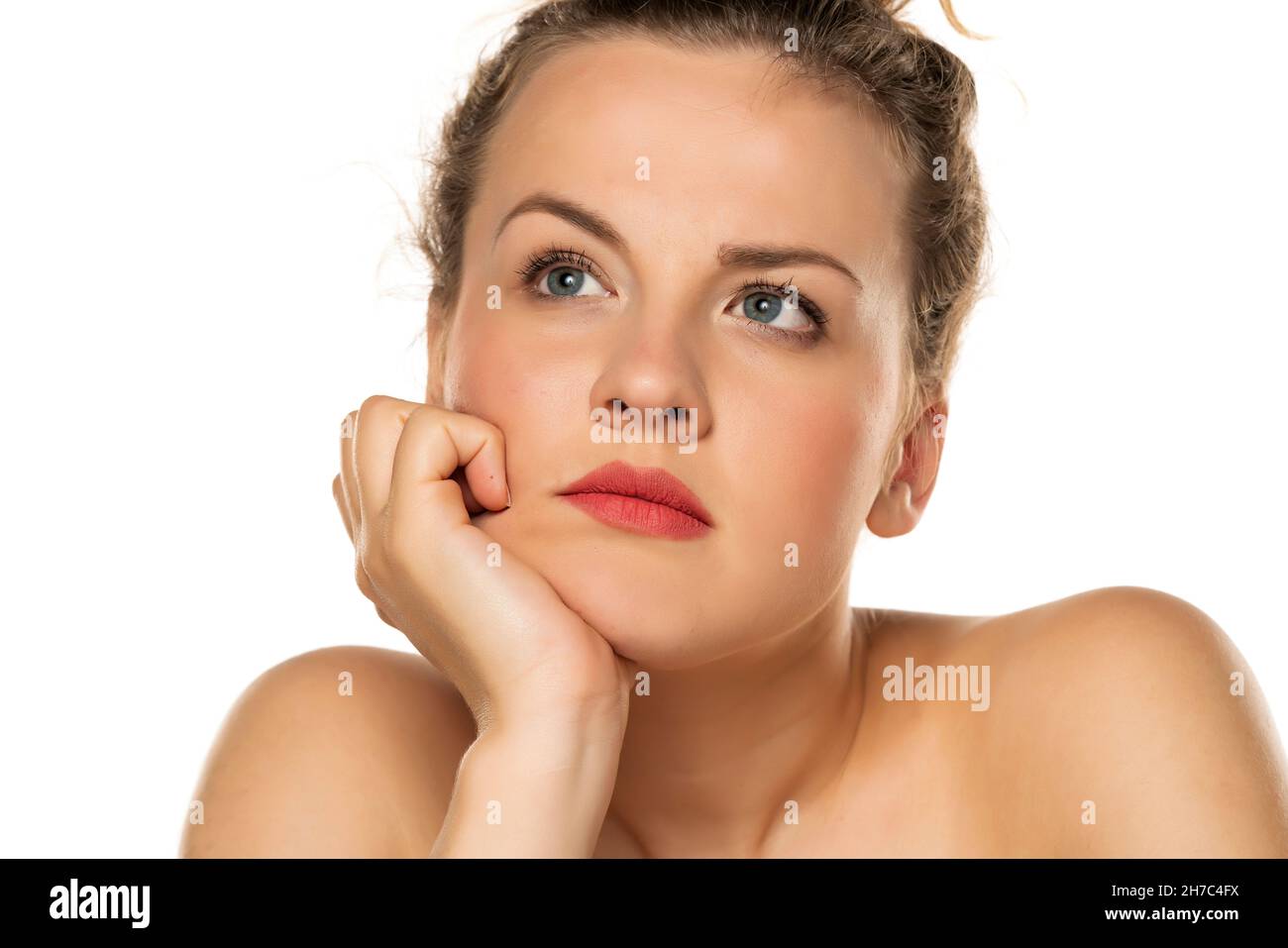 portrait of a blond frowning and thinking woman on a white background ...