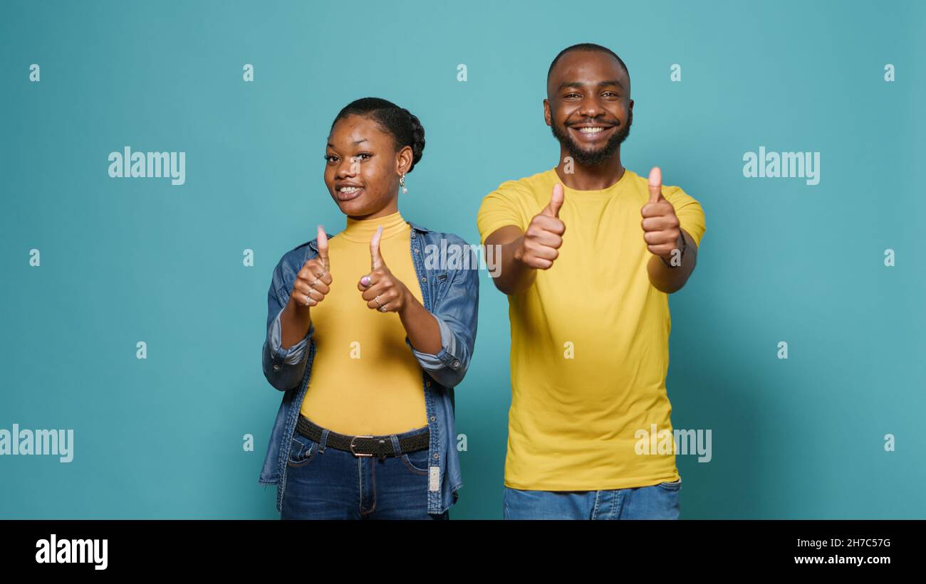 Man and woman doing thumbs up and okay gesture with hands on camera ...