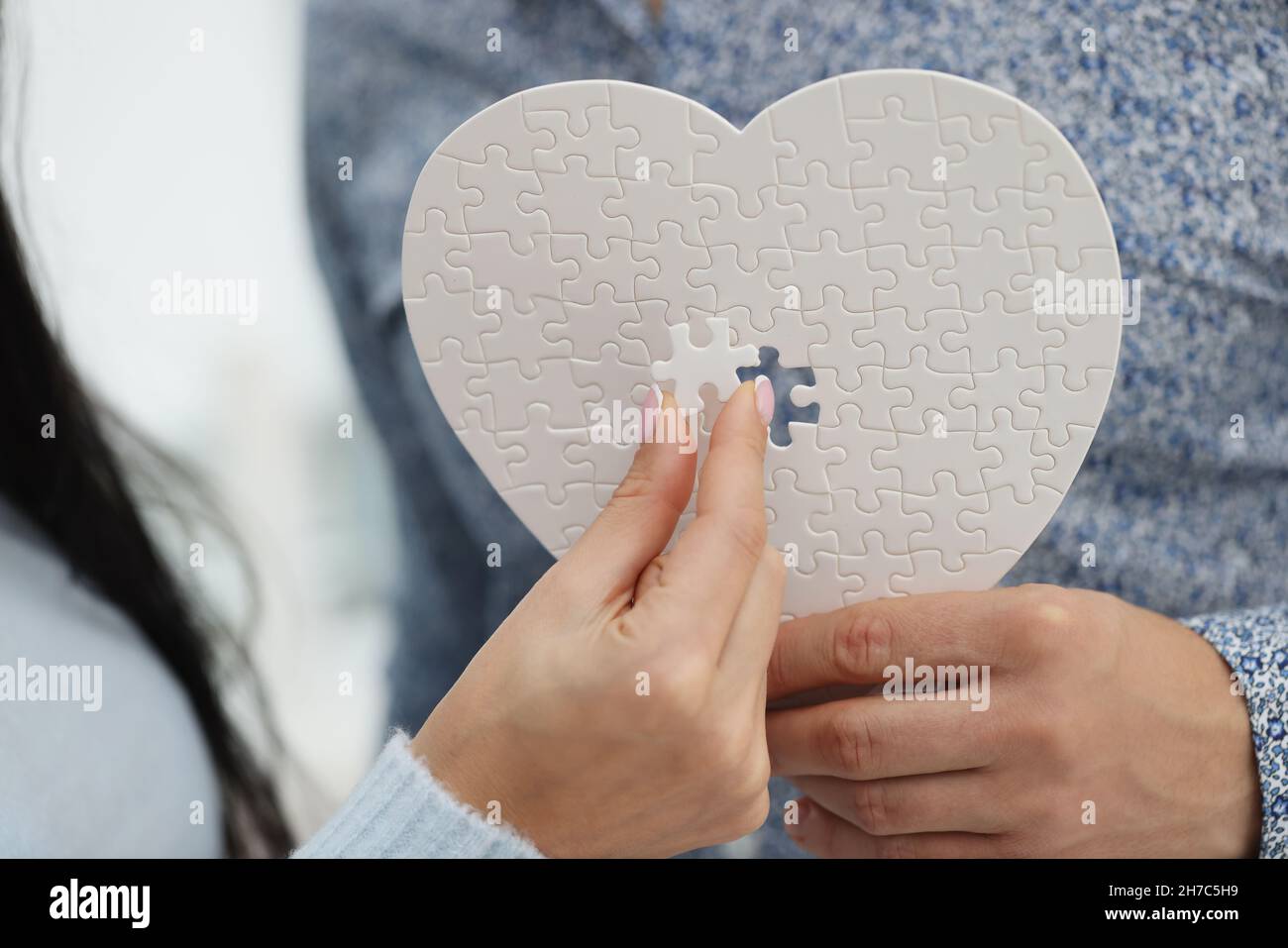 Woman filling empty space with missing piece of white heart puzzle ...