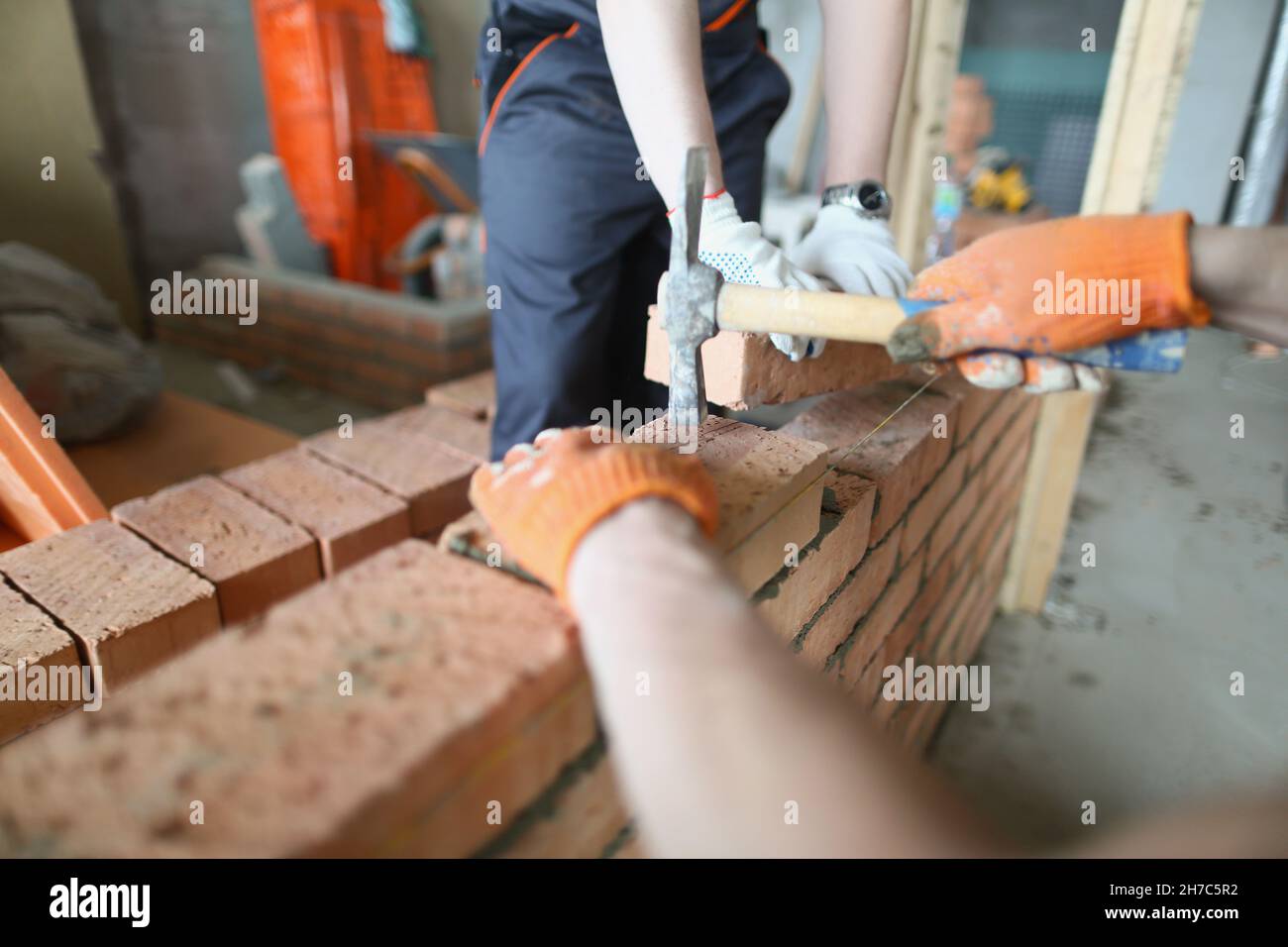 Qualified worker hit on red brick with hammer tool for better fixation ...