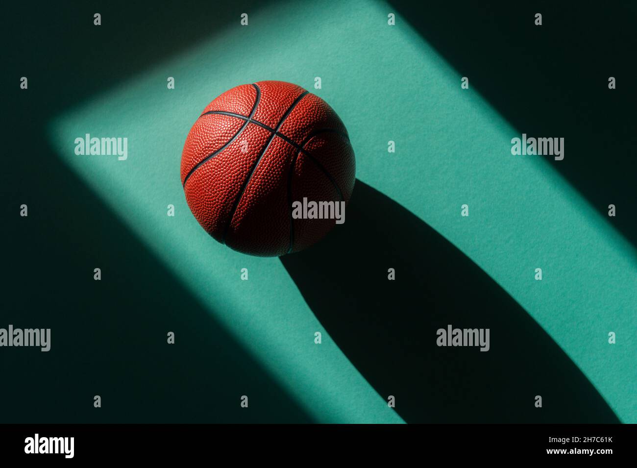Brown new basketball ball with natural lighting on green background ...
