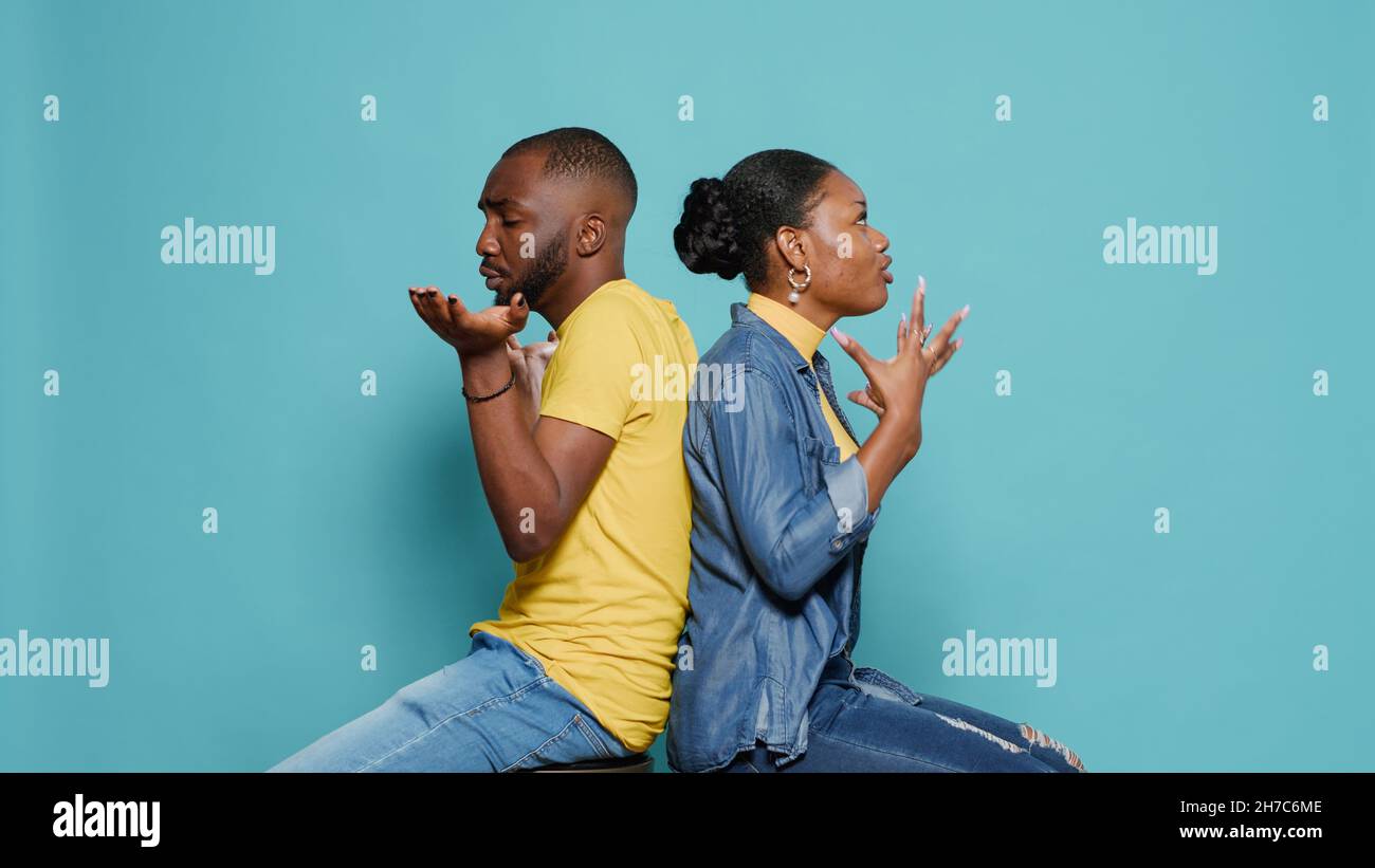 Frustrated man and woman sitting back to back and having argument in ...