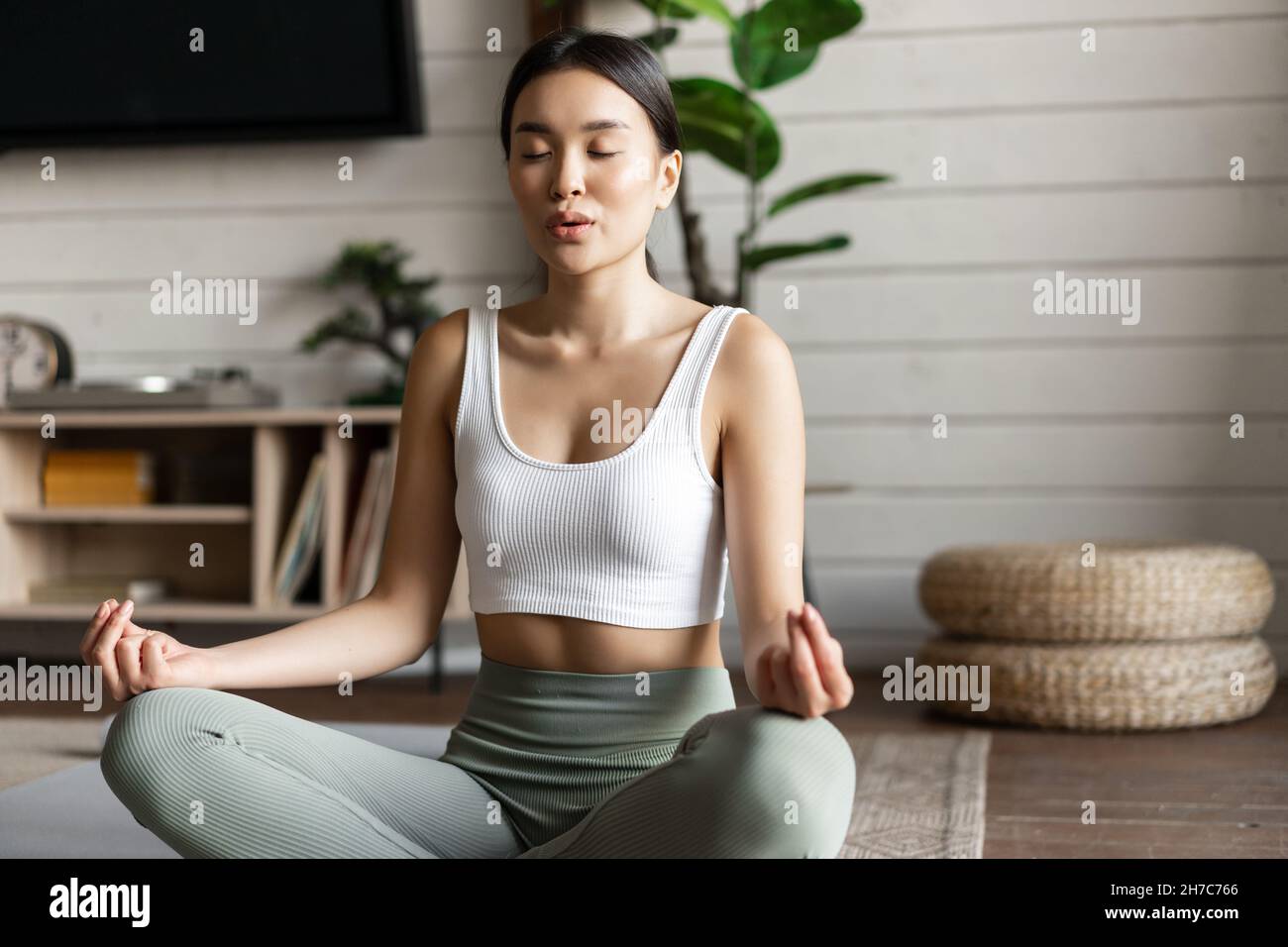 Mindfulness and meditation concept. Young asian woman doing workout at home, yoga meditation in ...