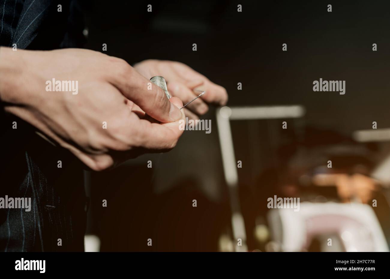 Tailor's hand. Male hands with a needle, thread and thimble. Conceptual ...