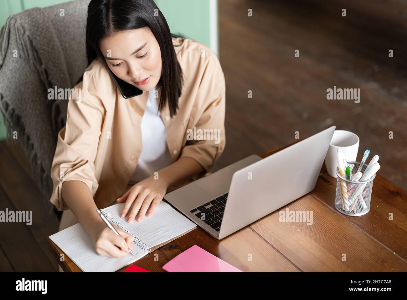 Upper angle shot of asian woman studying on phone, talking on mobile ...