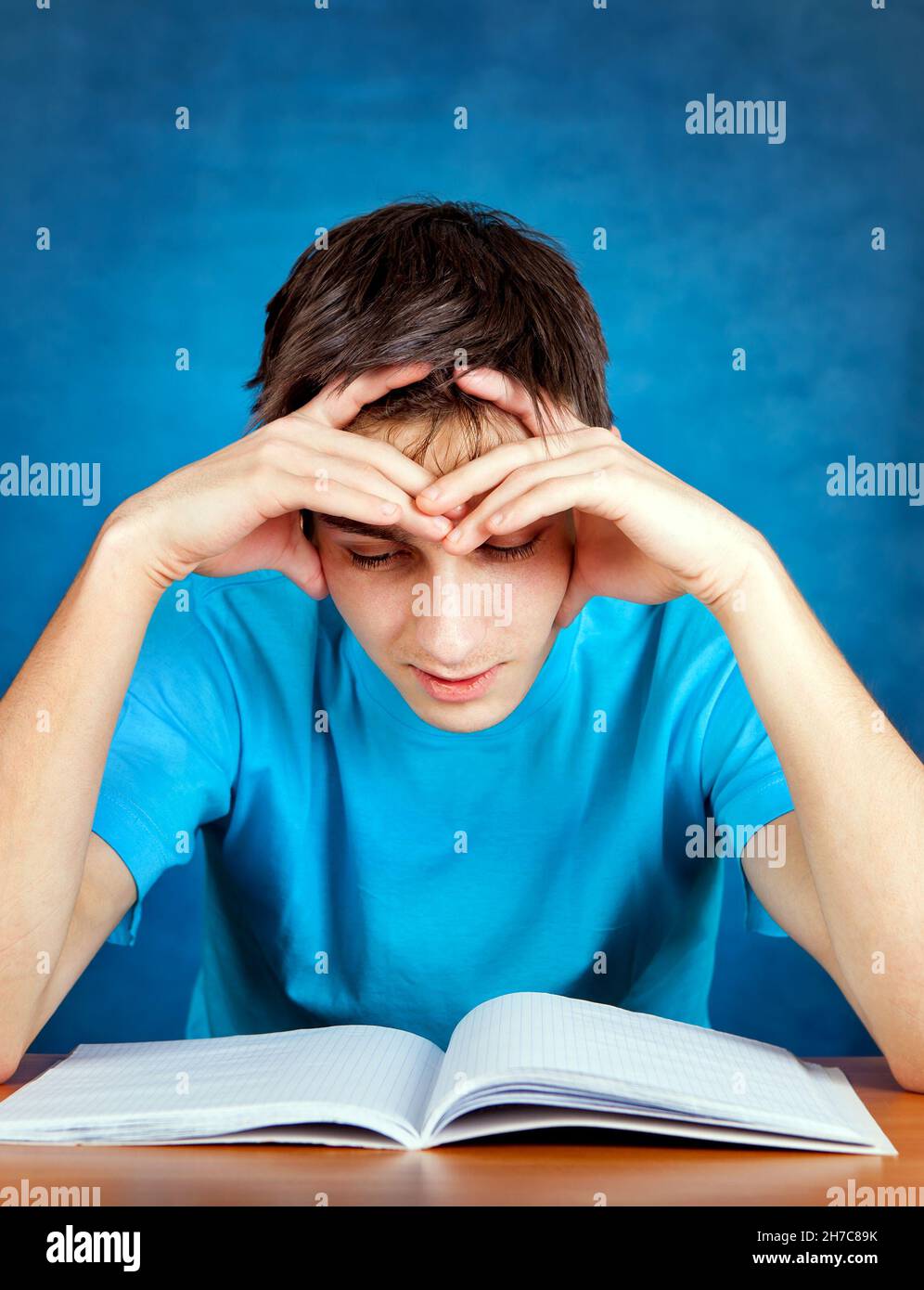 Tired Student read the Book on the Blue Background Stock Photo - Alamy