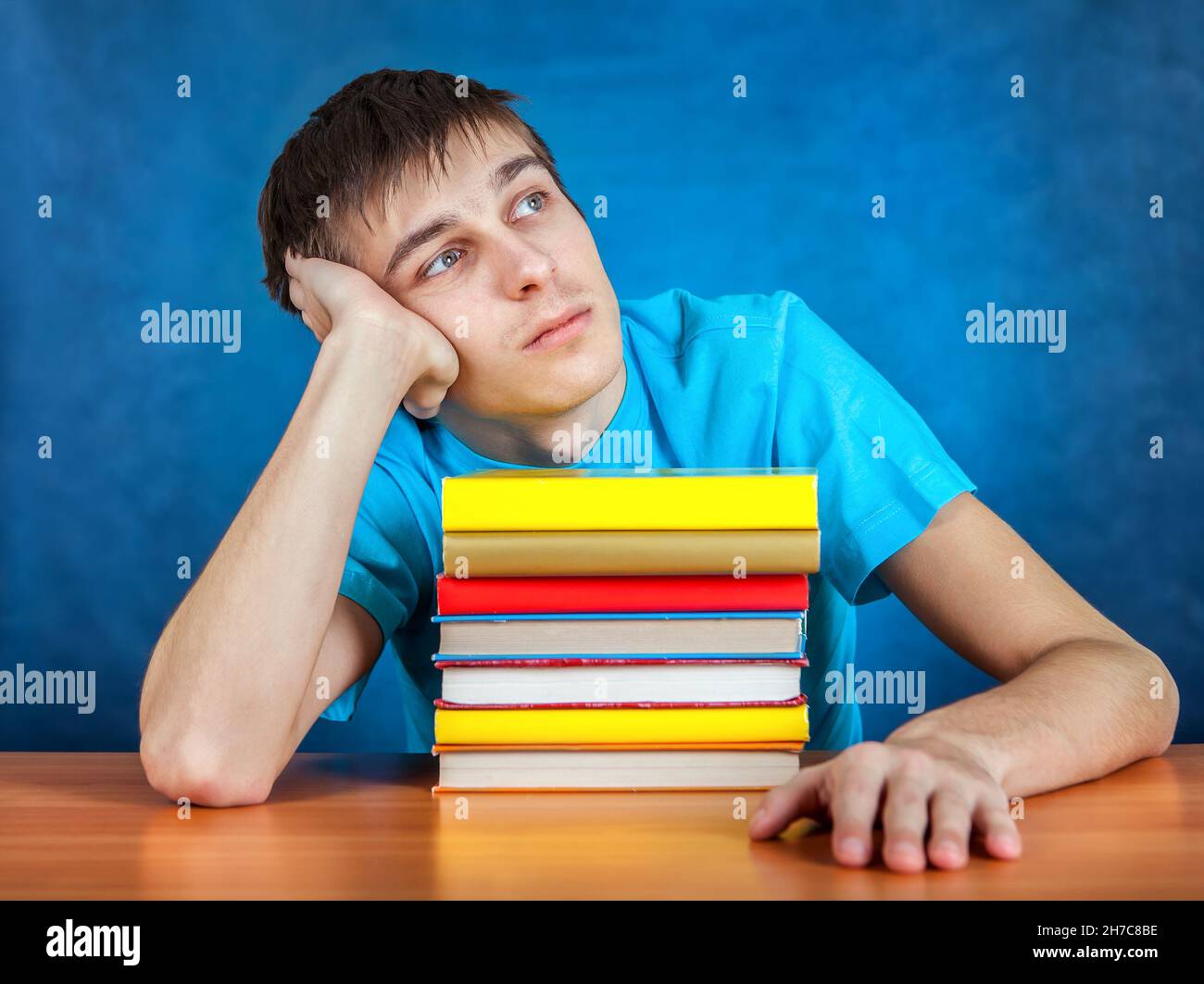Tired Student with the Book on the Blue Background Stock Photo - Alamy