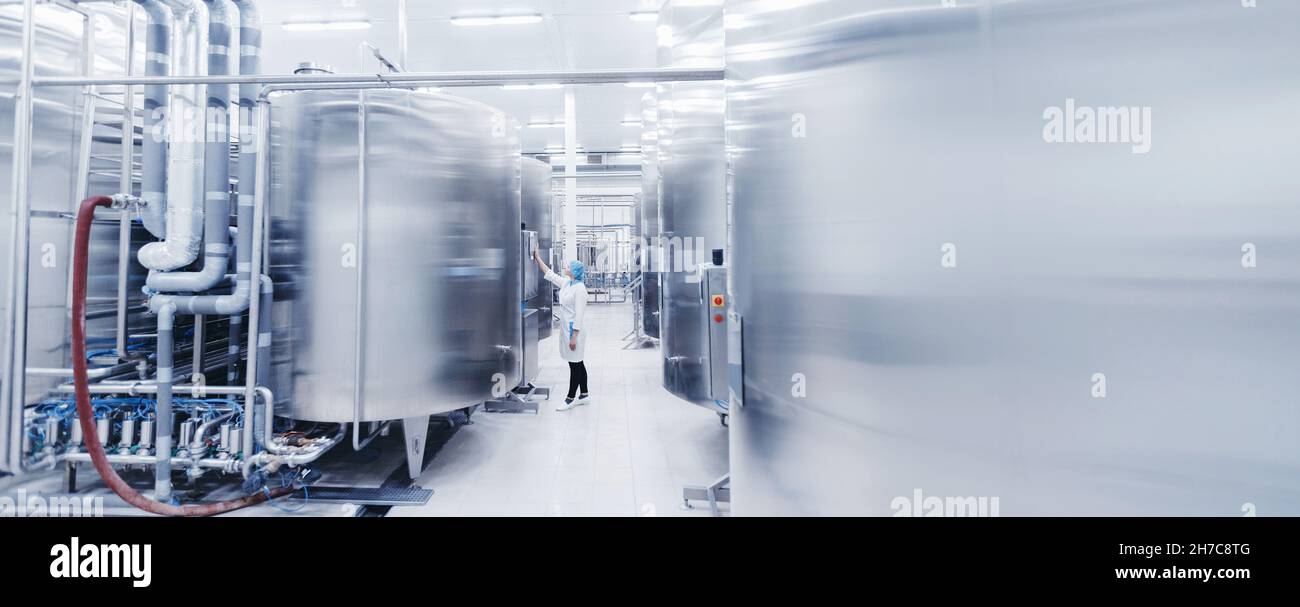 Worker female engineer operator in uniform uses process control panel ...