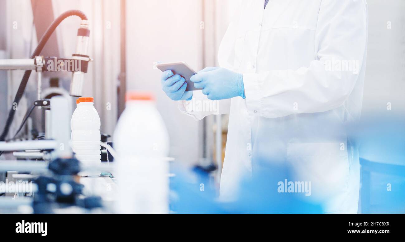 Engineer operator inspecting milk bottles production line dairy factory ...