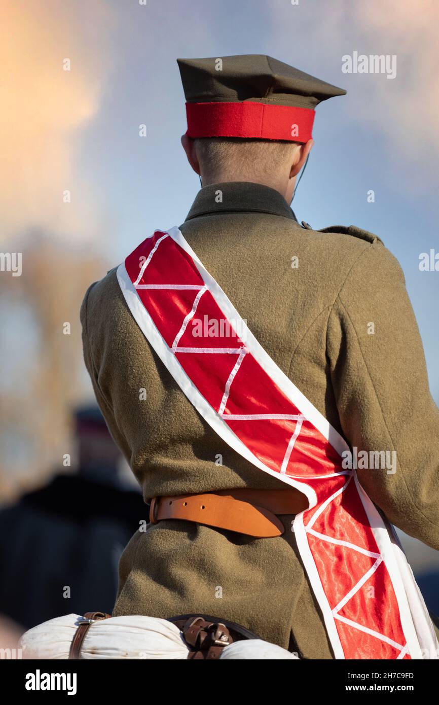 Rear view of a soldier sleeping with a red and white sash against a ...