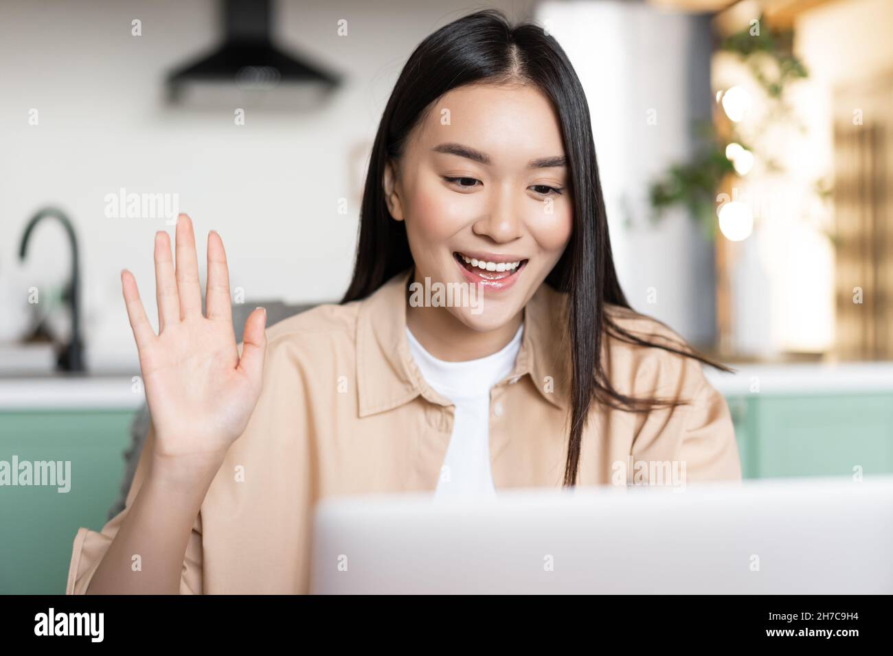 Smiling asian girl student waving hand at laptop camera. Woman on video ...
