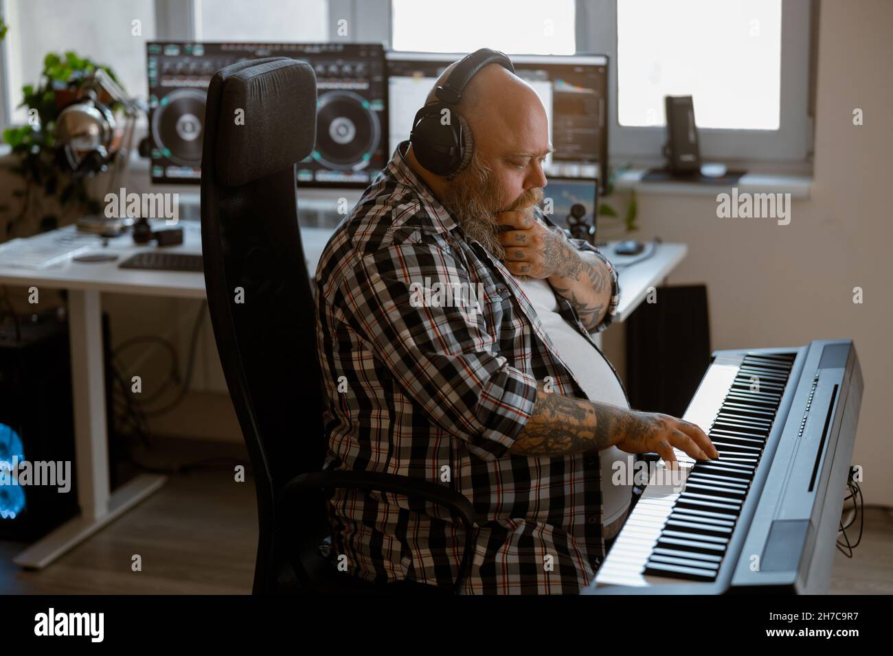 Thoughtfu man with headphones composes music on sound synthesizer in ...