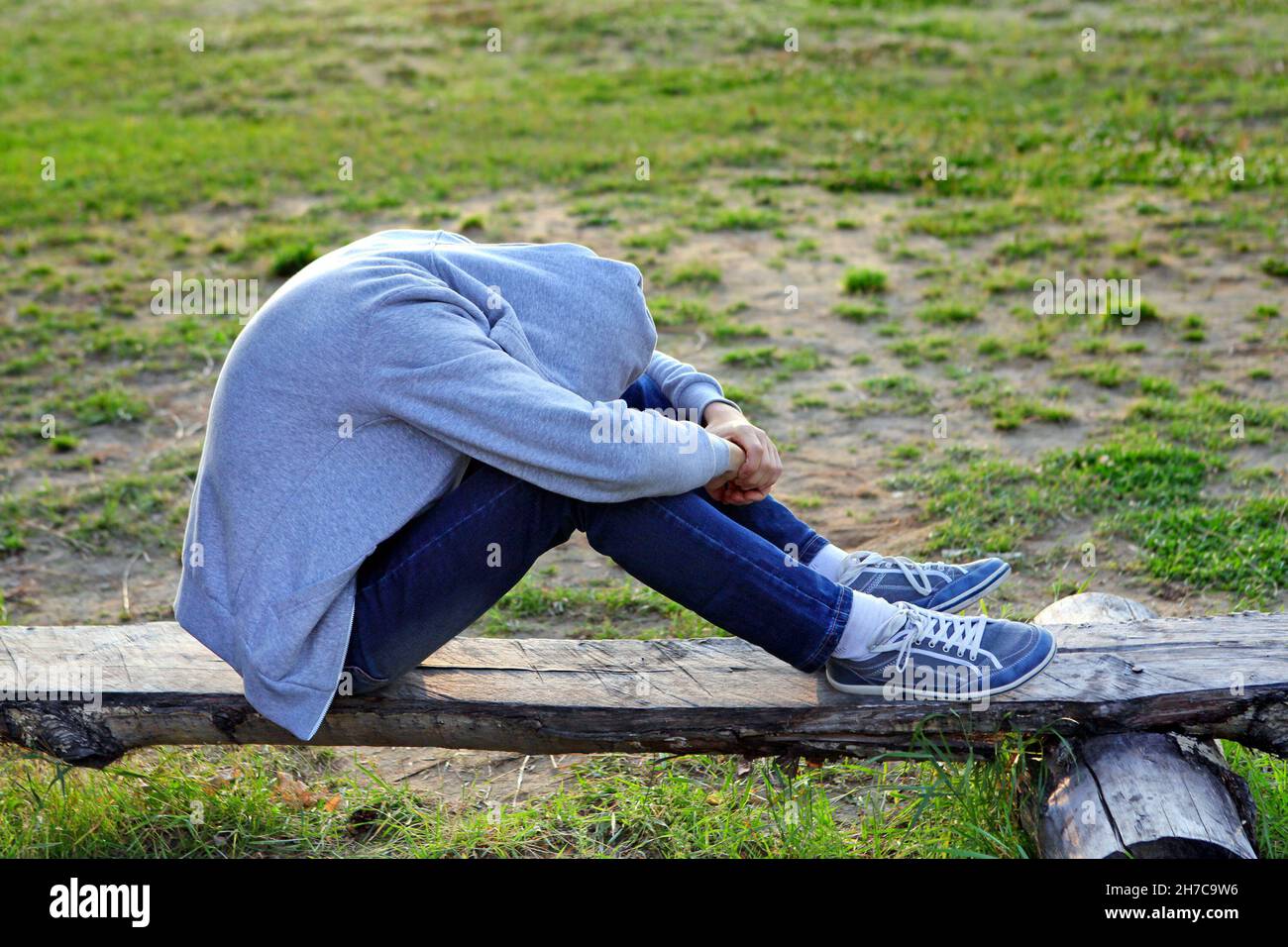 Sad Teenager in the Hood sit on the Log outdoor Stock Photo - Alamy