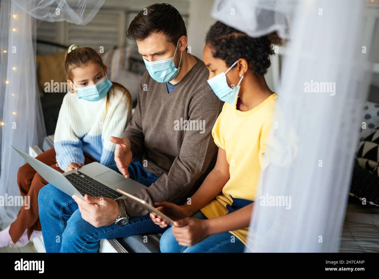 Multiethnic children with father studying online at home on computer ...
