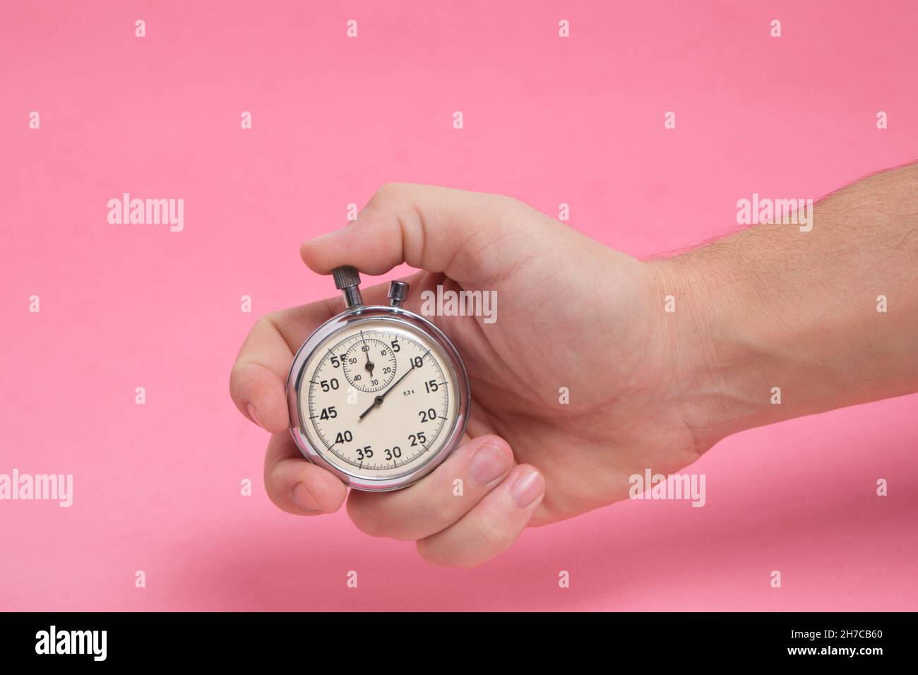 Man hand holding stopwatch on pink background Stock Photo - Alamy