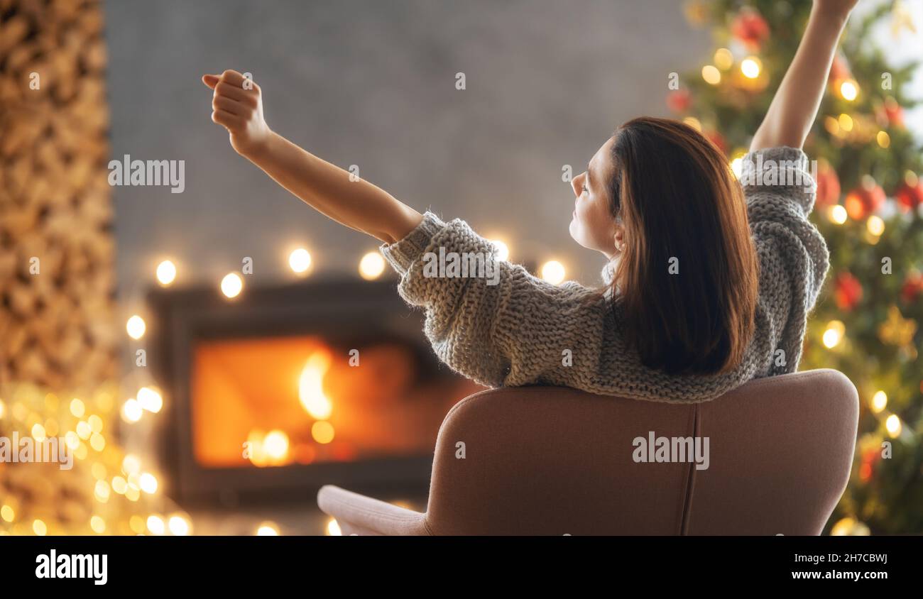 Young woman is relaxing near Christmas tree at home Stock Photo - Alamy