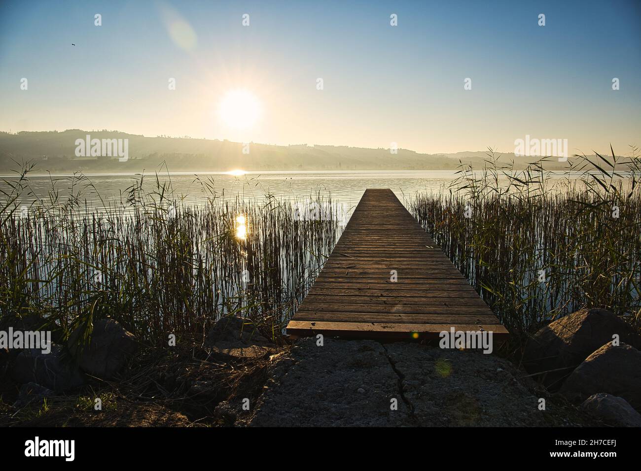 Wooden deck at the shore of a lake in Sempach, Switzerland, surrounded ...