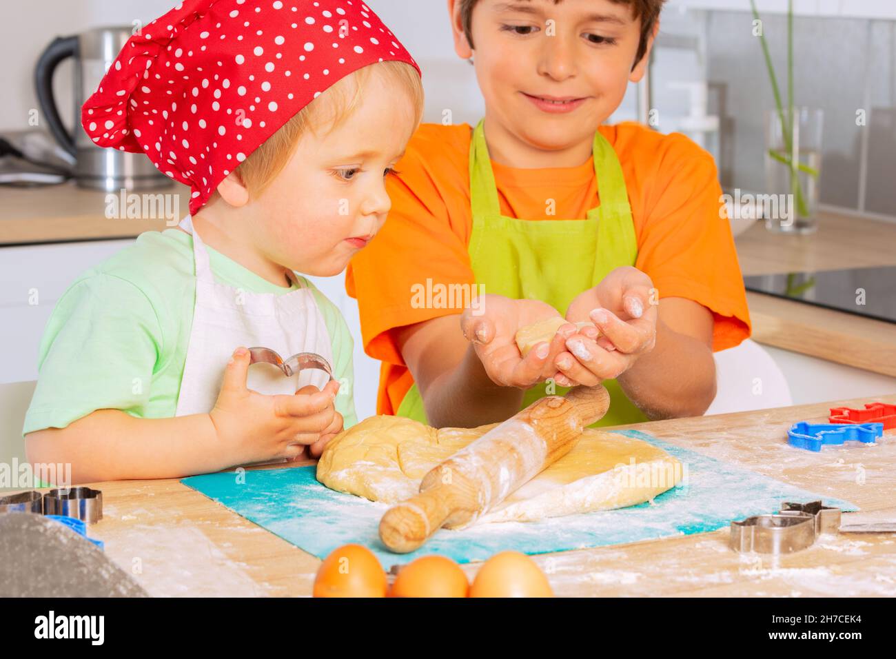 Two kids roll dough and cut shapes on the kitchen Stock Photo - Alamy