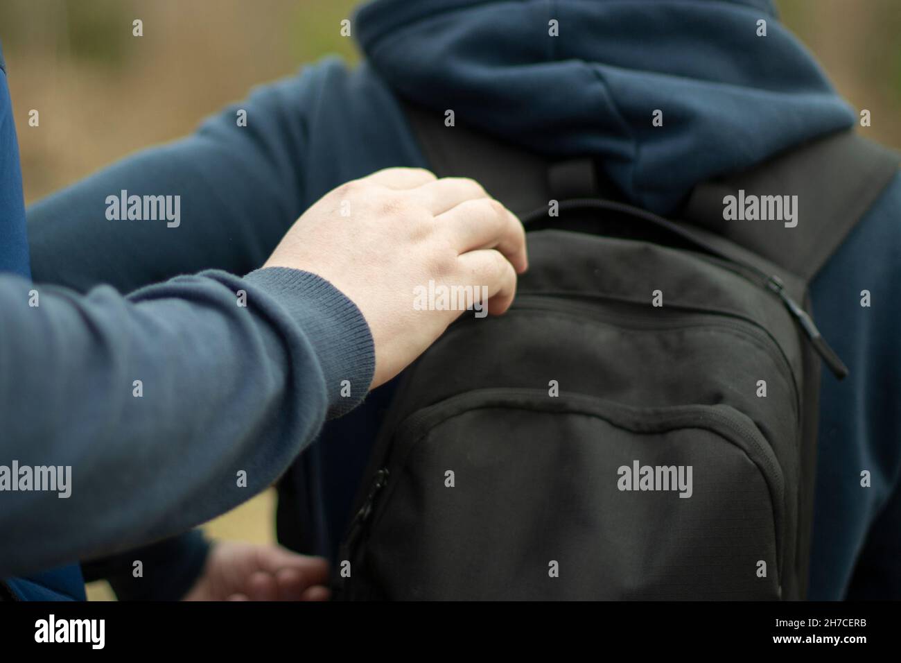 The guy is in a backpack. A man takes things from a friend's bag. A ...