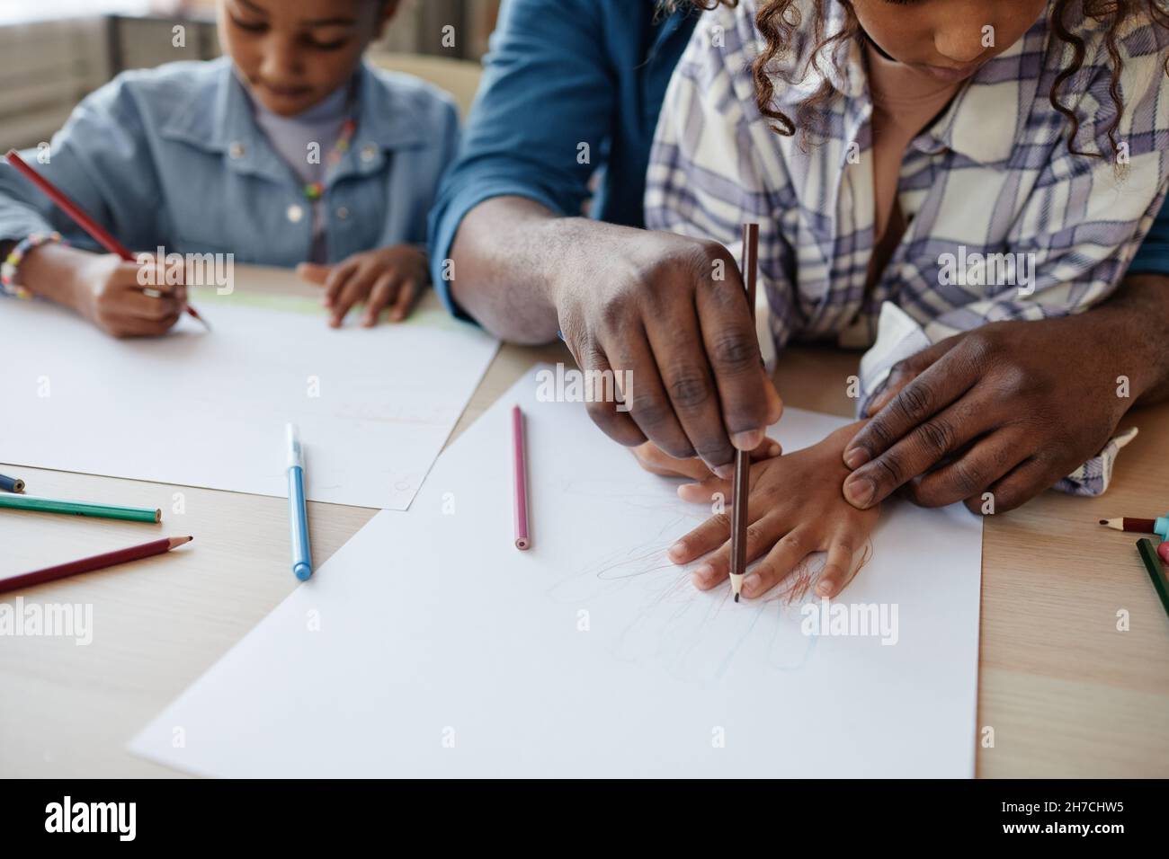 Close up of African-American father with two girls drawing together at ...