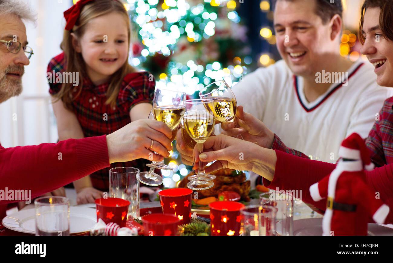 Family with children eating Christmas dinner at fireplace and decorated ...